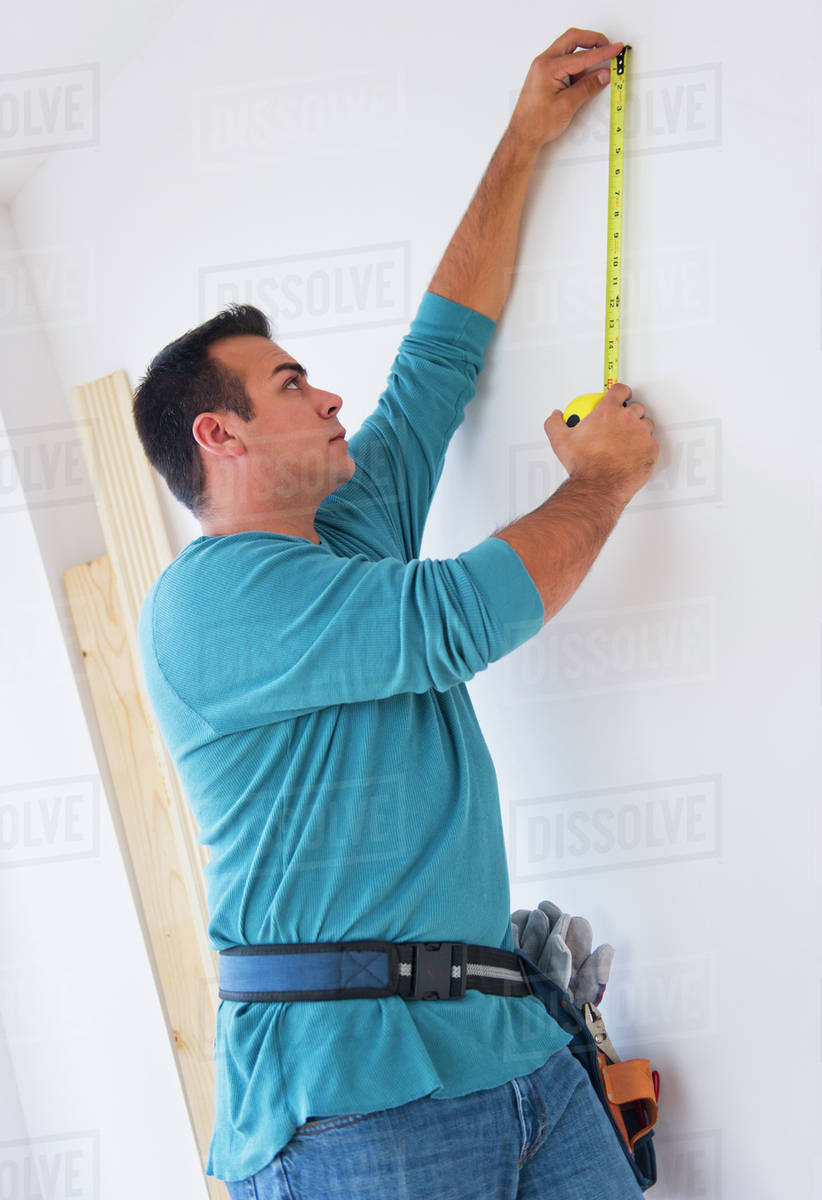 Construction worker measuring wall - Stock Photo - Dissolve