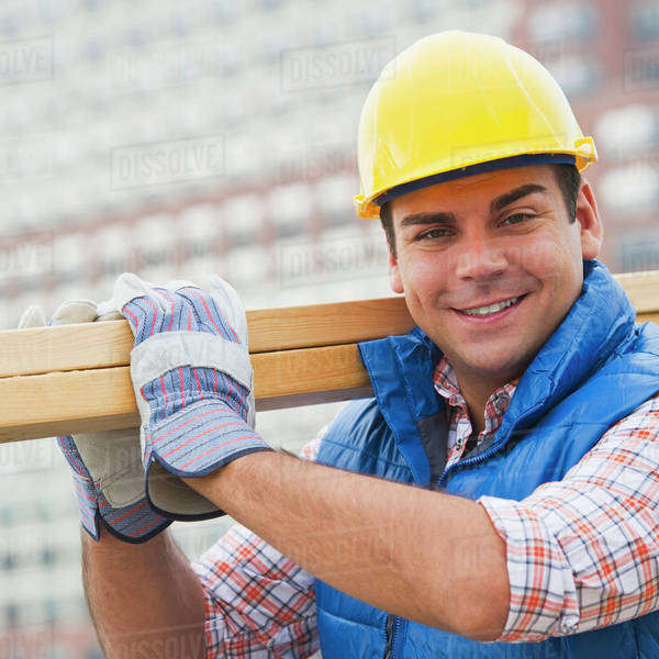 Construction worker carrying planks on construction site - Royalty-free ...