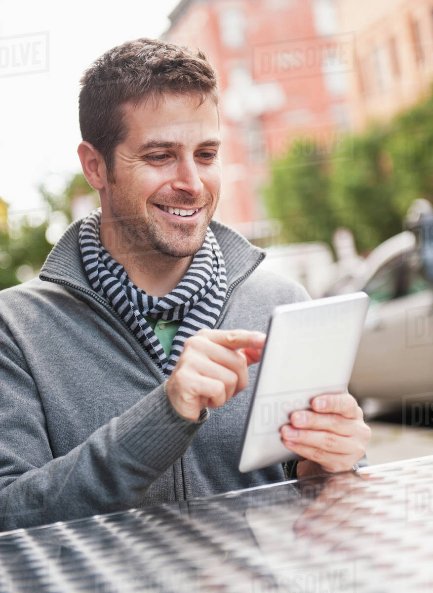 Man with digital tablet sitting in outdoor cafe - Stock Photo - Dissolve