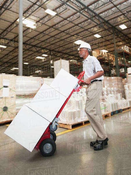 Man pushing hand truck in warehouse - Royalty-free Stock Photo | Dissolve
