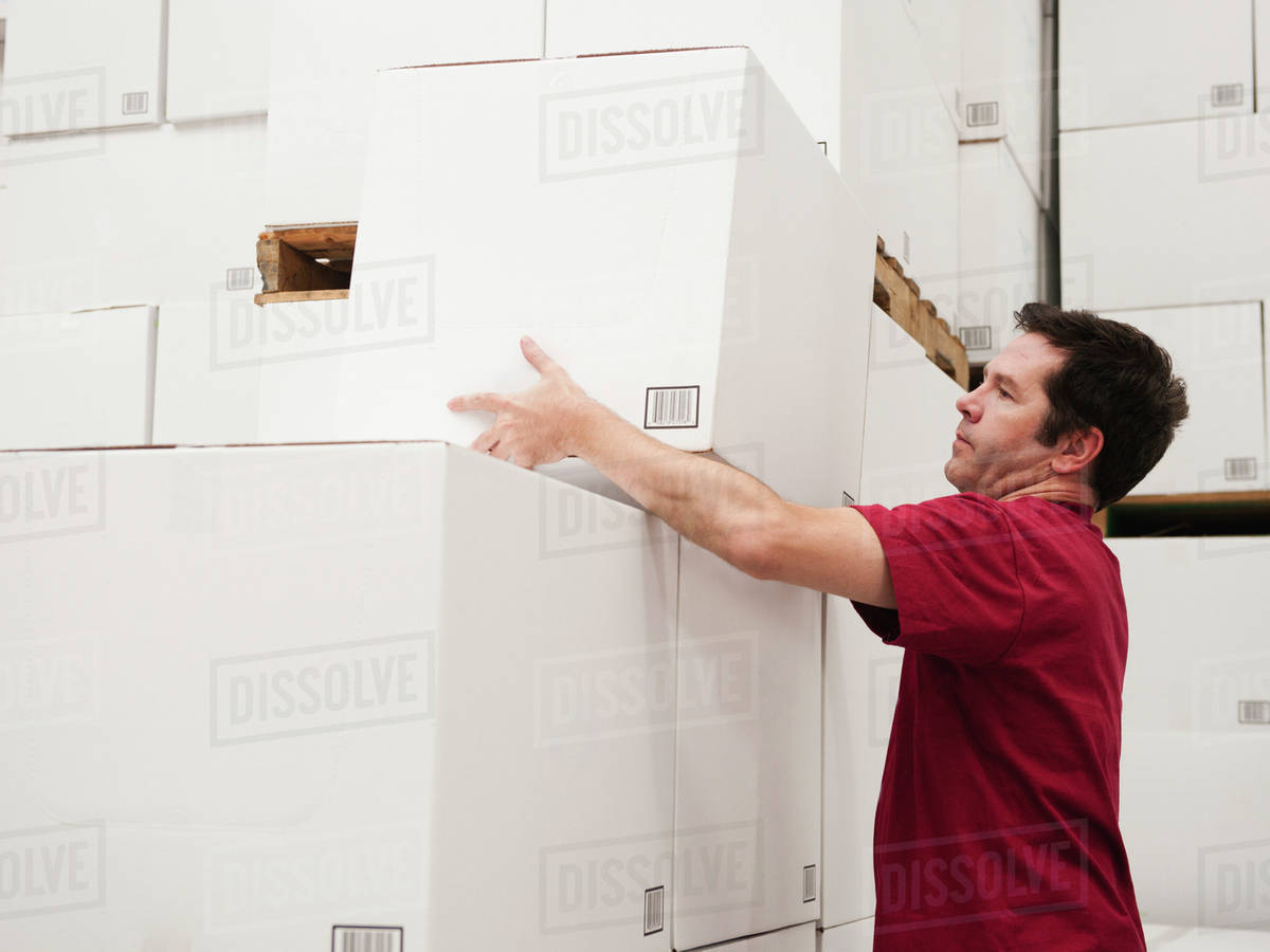 Worker stacking boxes in warehouse - Royalty-free Stock Photo | Dissolve