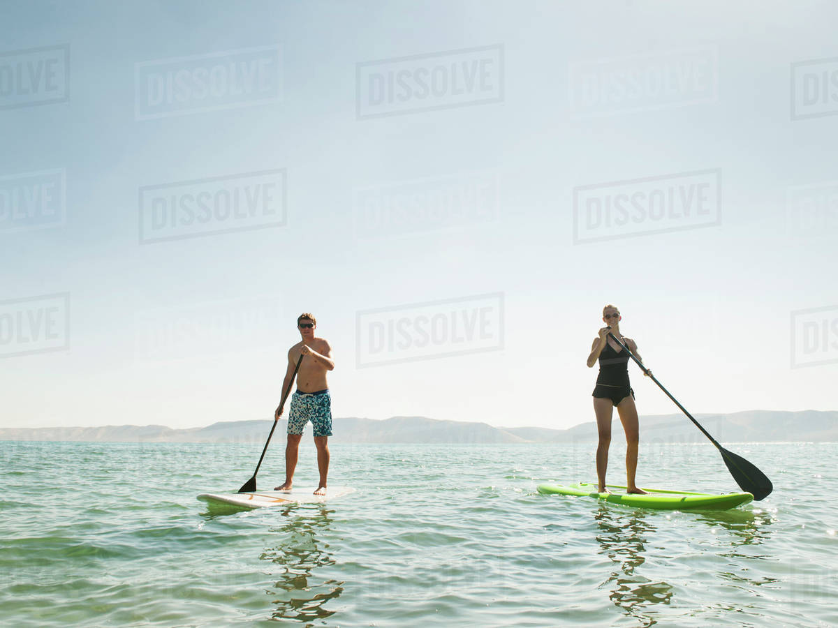 Two people standing on paddleboard - Royalty-free Stock Photo | Dissolve