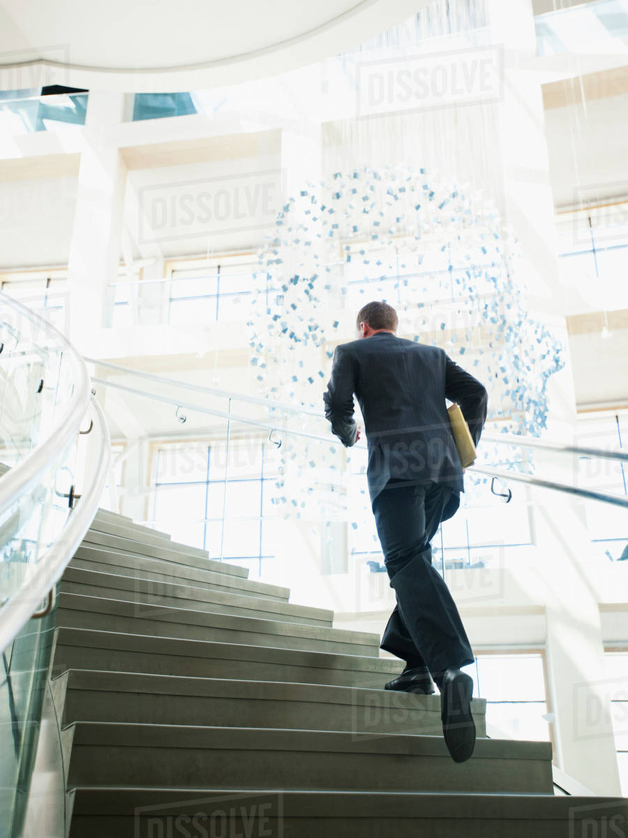Rear view of man running up stairs - Stock Photo - Dissolve
