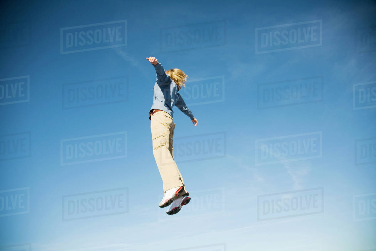 Woman in floating in blue sky with arms outstretched - Stock Photo ...