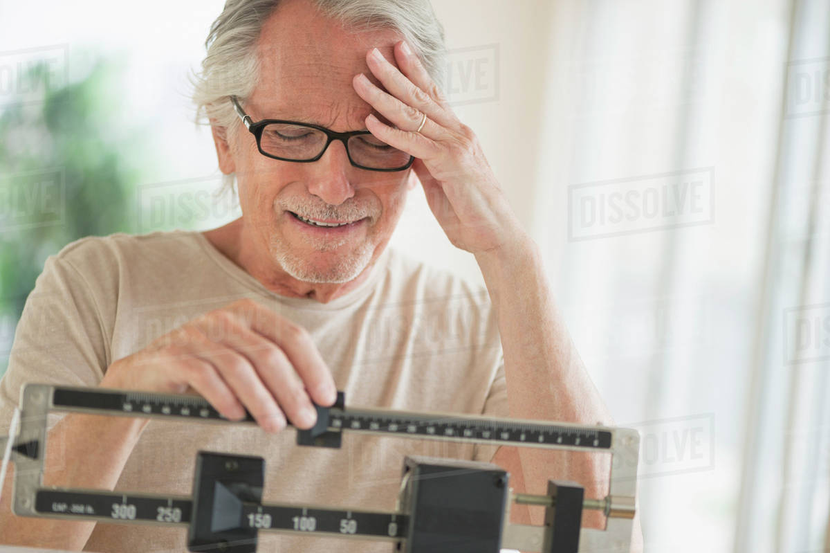 Senior man on weight scale - Stock Photo - Dissolve