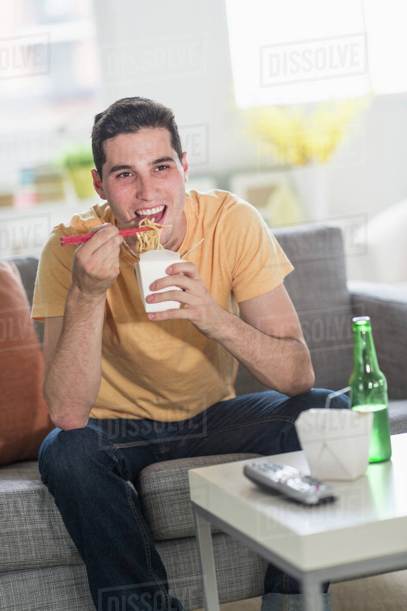 Man eating take out meal and watching television - Stock Photo - Dissolve