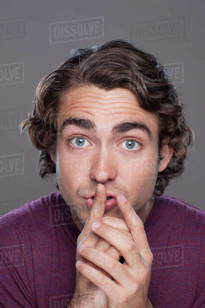 Studio shot of young man with finger on his lips - Royalty-free Stock ...