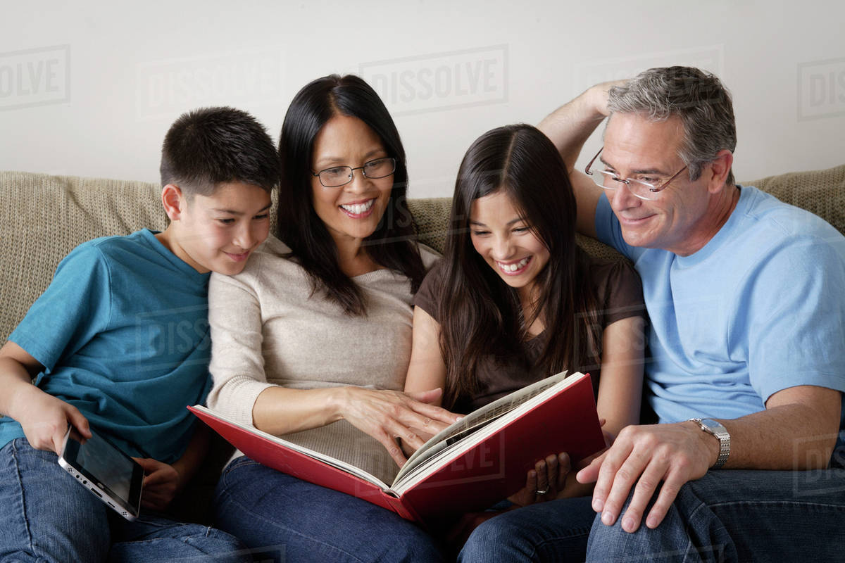 Family watching photo album together - Royalty-free Stock Photo | Dissolve