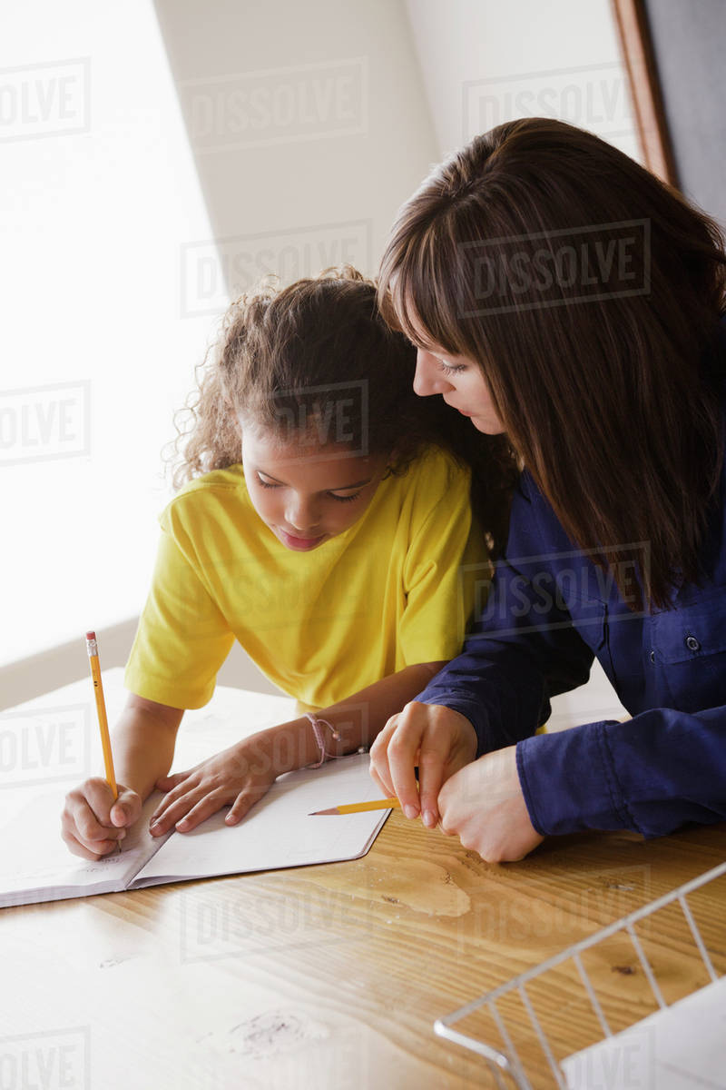 Schoolgirl writing with teacher in classroom - Royalty-free Stock Photo ...