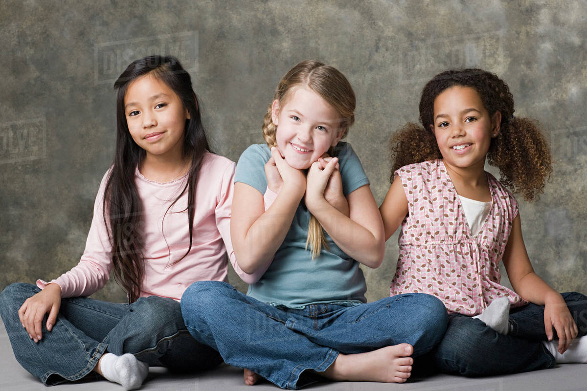 Portrait of three smiling girls (8-9) sitting together, studio shot ...