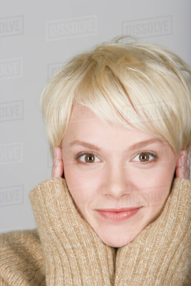Studio shot portrait of mid adult woman with hand on chin, close-up ...