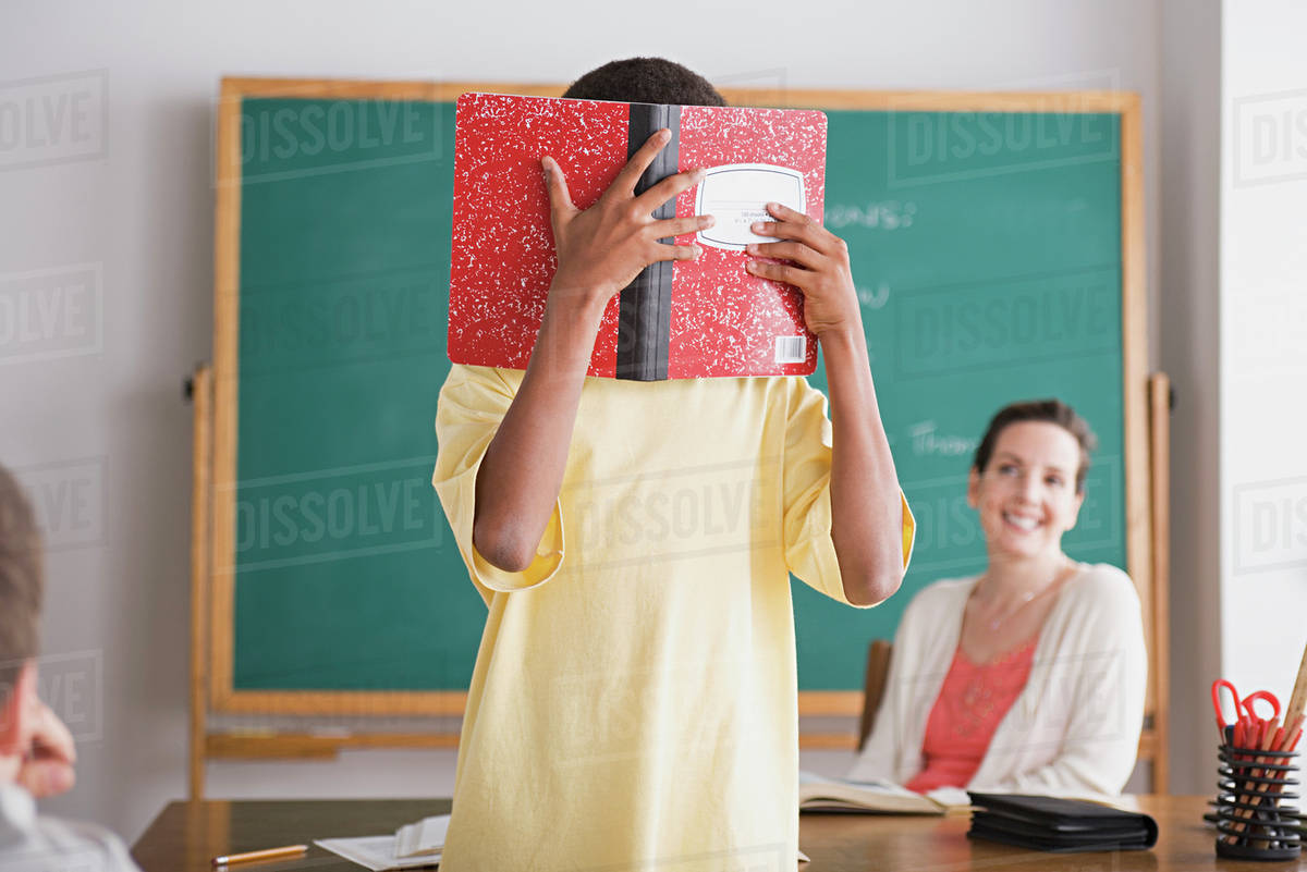 Boy reading from book in classroom - Royalty-free Stock Photo | Dissolve