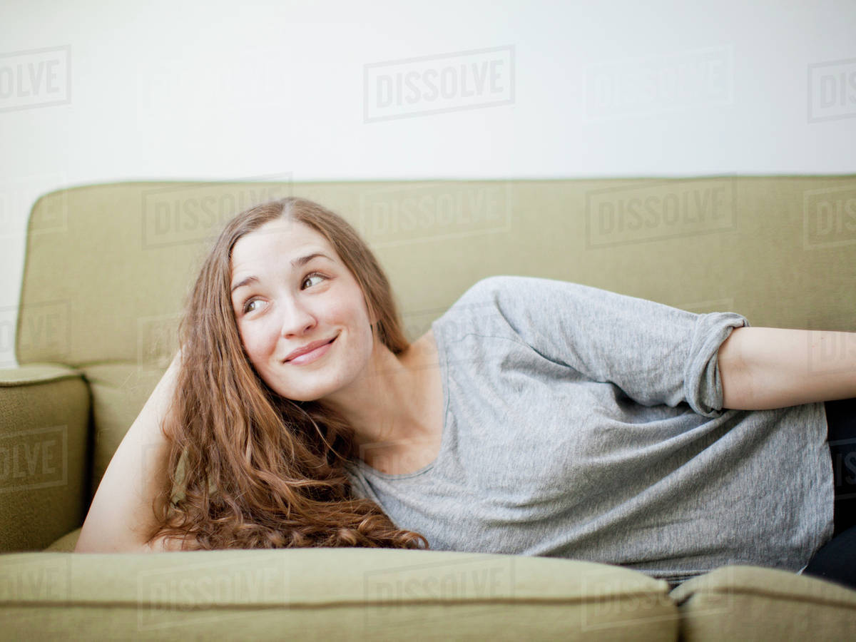 Happy young woman reclining on sofa - Royalty-free Stock Photo | Dissolve