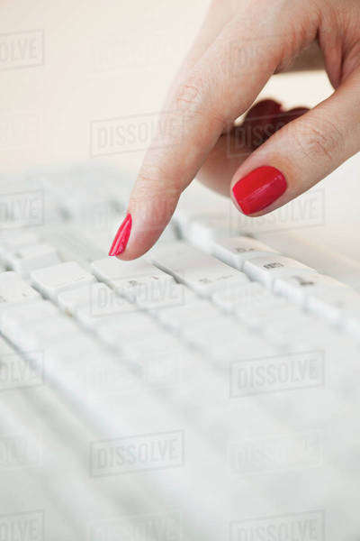 Close up of woman's finger with red nail polish typing on computer ...