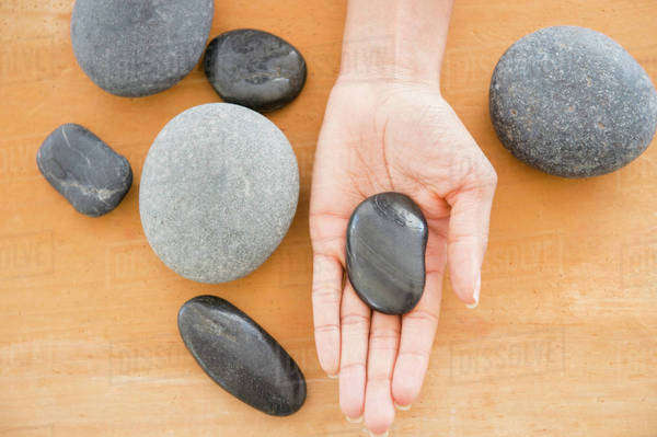 Close up of woman's hand holding pebble - Stock Photo - Dissolve
