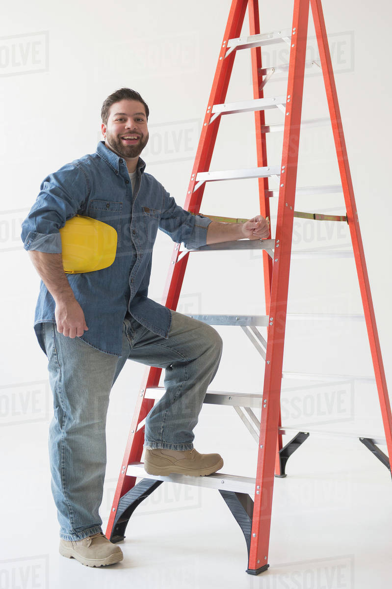 Portrait of construction worker standing by ladder - Stock Photo - Dissolve