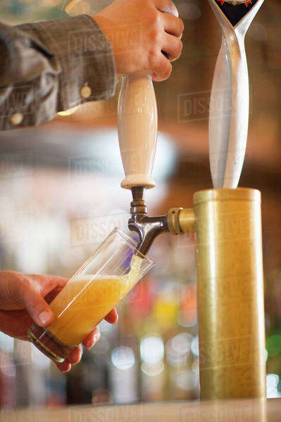 Barman poring beer from beer tap - Royalty-free Stock Photo | Dissolve