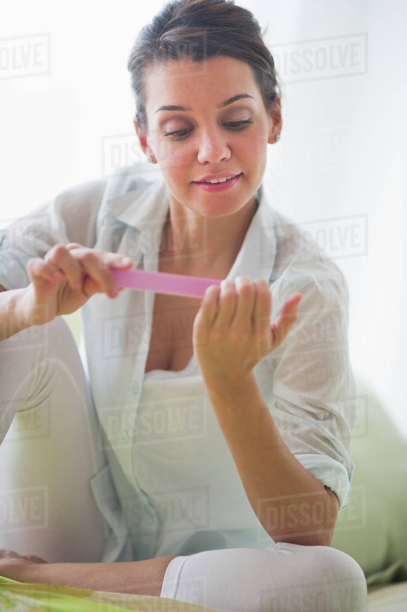 Attractive young woman filing nails - Royalty-free Stock Photo | Dissolve