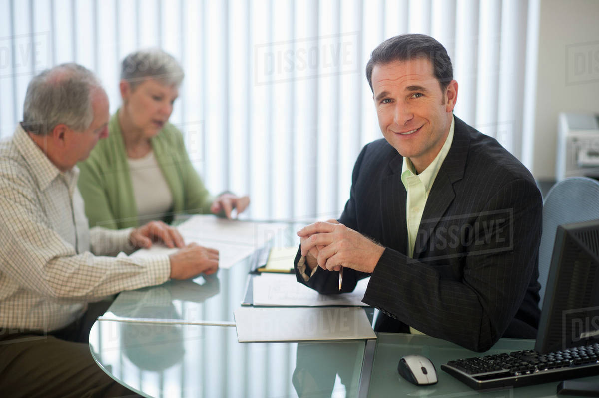 Senior couple talking to man in office - Stock Photo - Dissolve