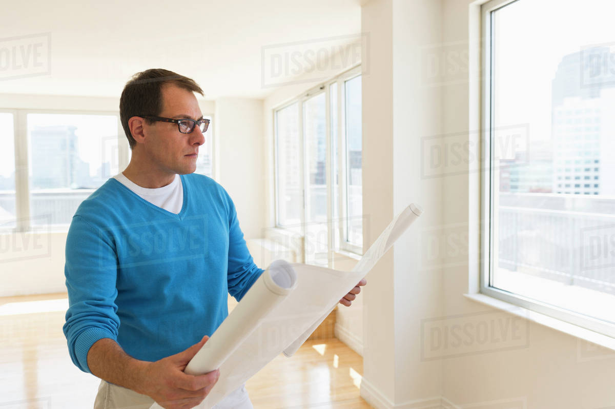 Architect reading blueprint in new office - Stock Photo - Dissolve
