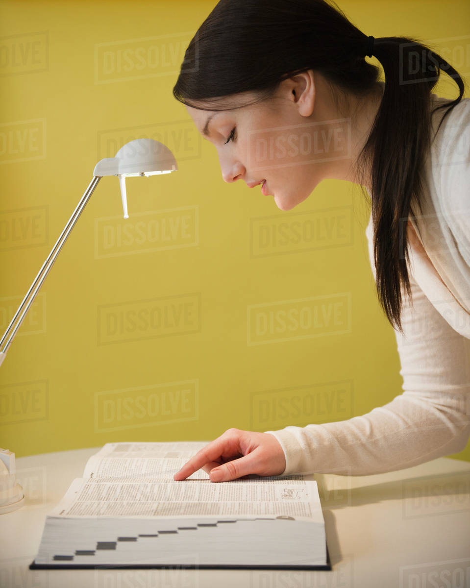 Young woman looking at dictionary - Stock Photo - Dissolve