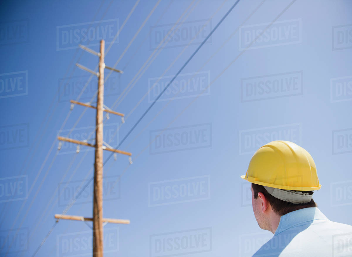 Man in hard hat looking at telephone pole - Royalty-free Stock Photo ...