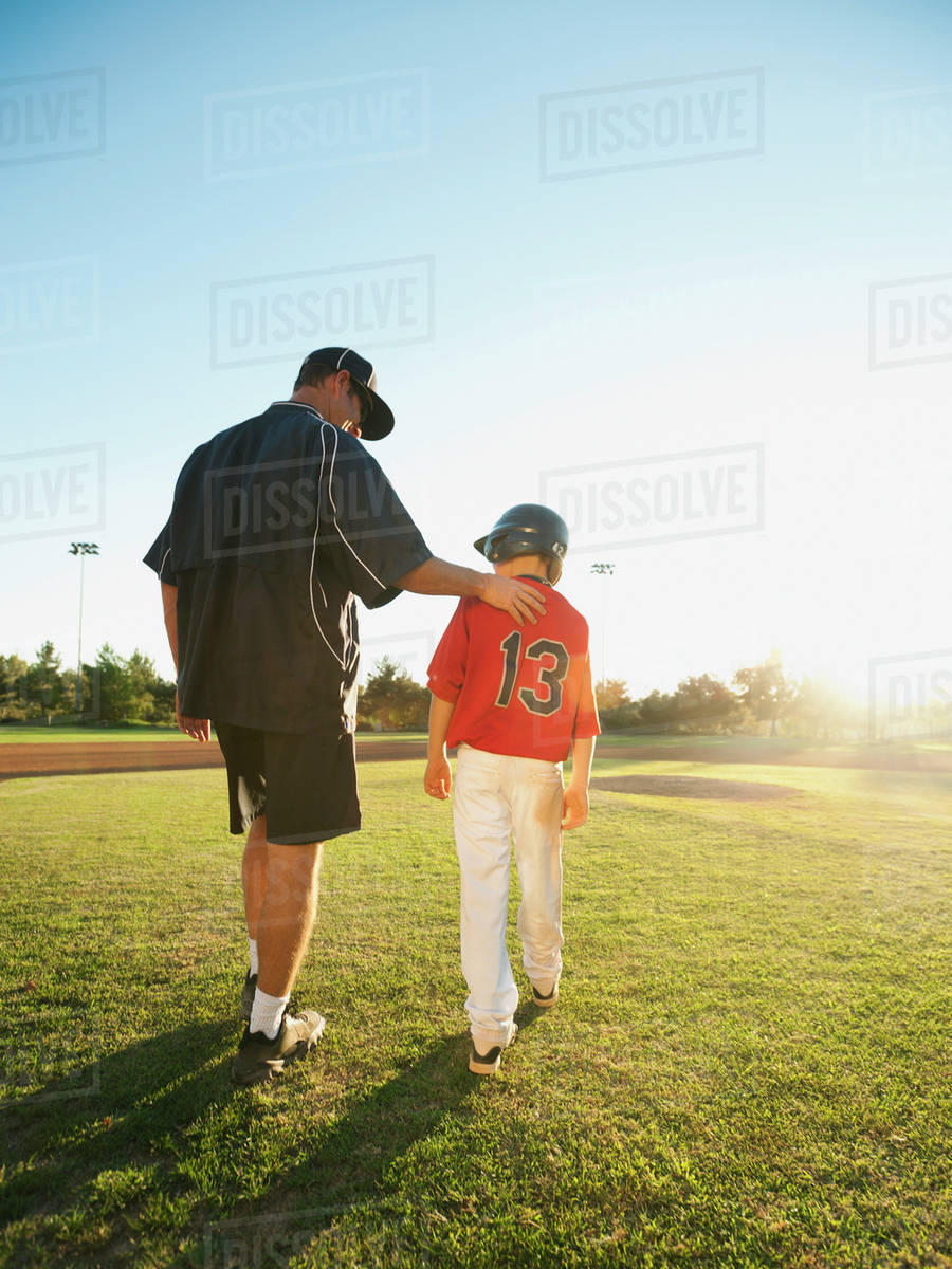 USA, California, Ladera Ranch, man and boy (10-11) walking on baseball ...