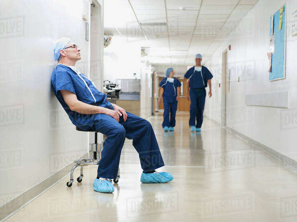 Surgeon resting in hospital corridor after operation, while two of his ...