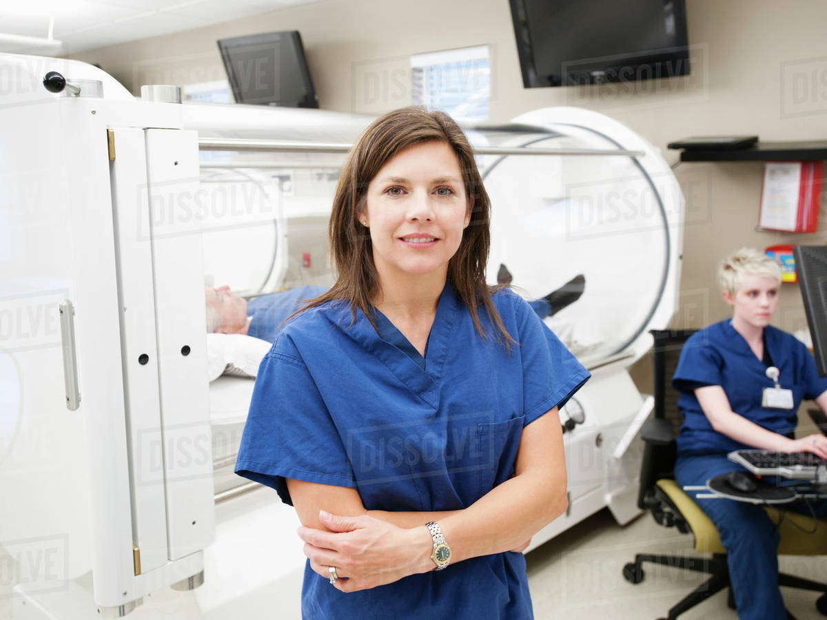 Young female nurse standing in front of CAT scanner - Royalty-free ...