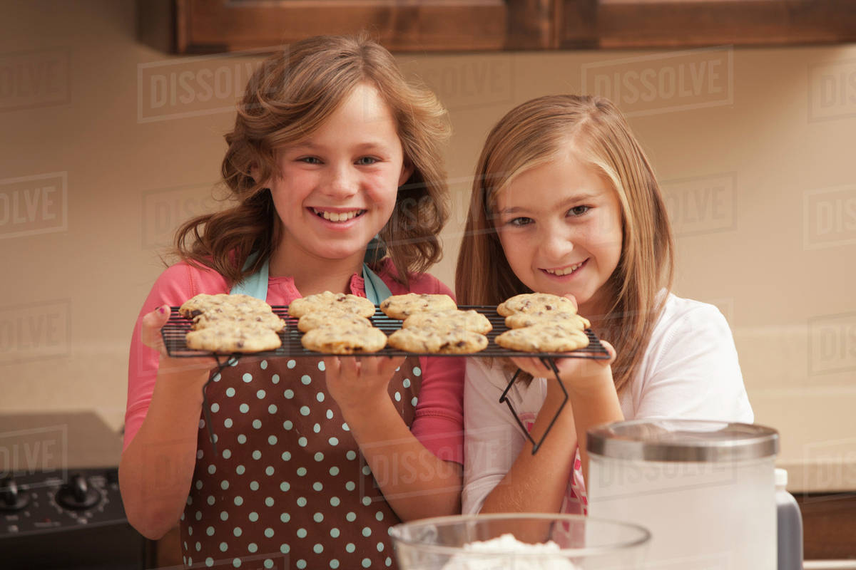 Portrait of two girls (10-11) holding biscuits in kitchen - Royalty ...