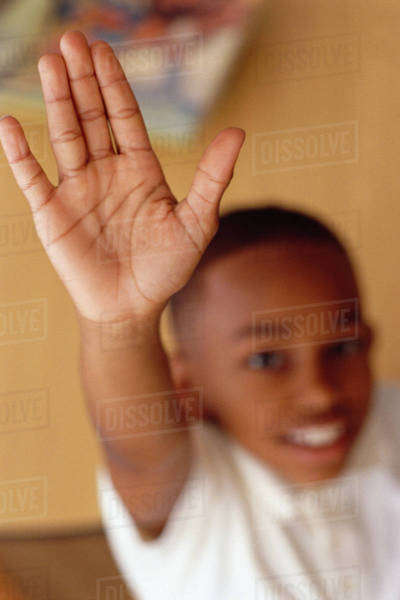 Child raising hand in classroom - Stock Photo - Dissolve