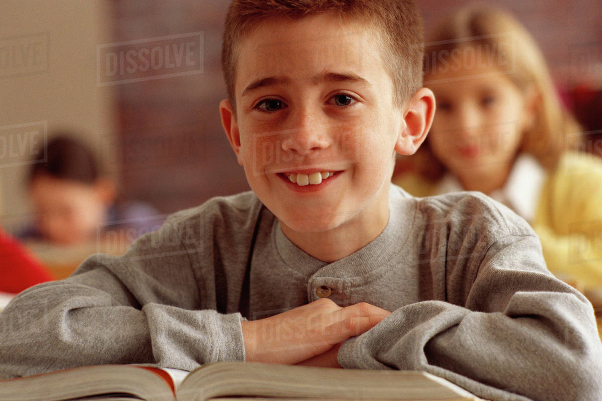 Student sitting at desk in classroom - Stock Photo - Dissolve