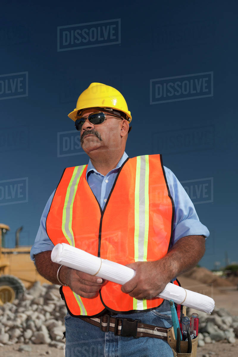 Construction worker holding blueprint on building site - Royalty-free ...