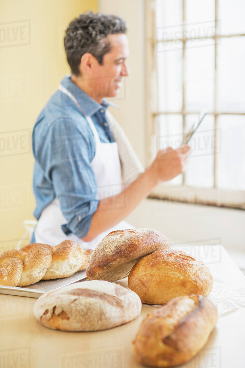 Side view of baker using digital tablet - Stock Photo - Dissolve