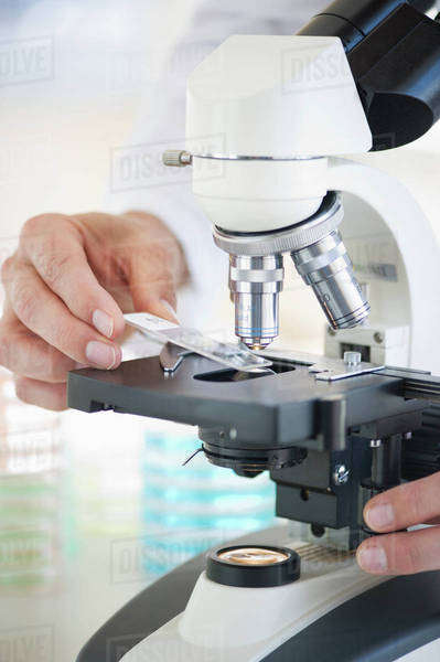 Hands on a microscope - Royalty-free Stock Photo | Dissolve