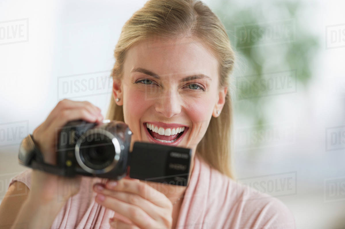 Woman laughing while taking a video - Stock Photo - Dissolve