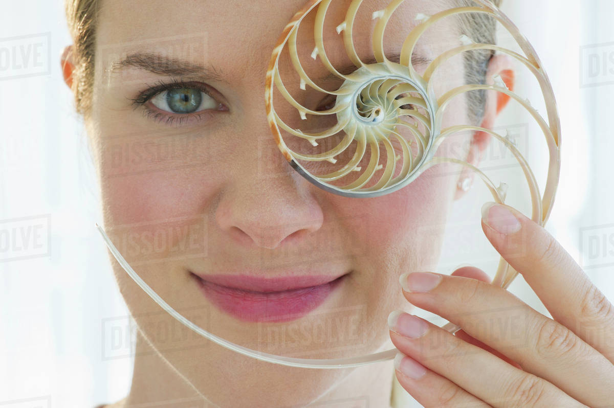 Woman holding a nautilus shell in front of her eye - Royalty-free Stock ...