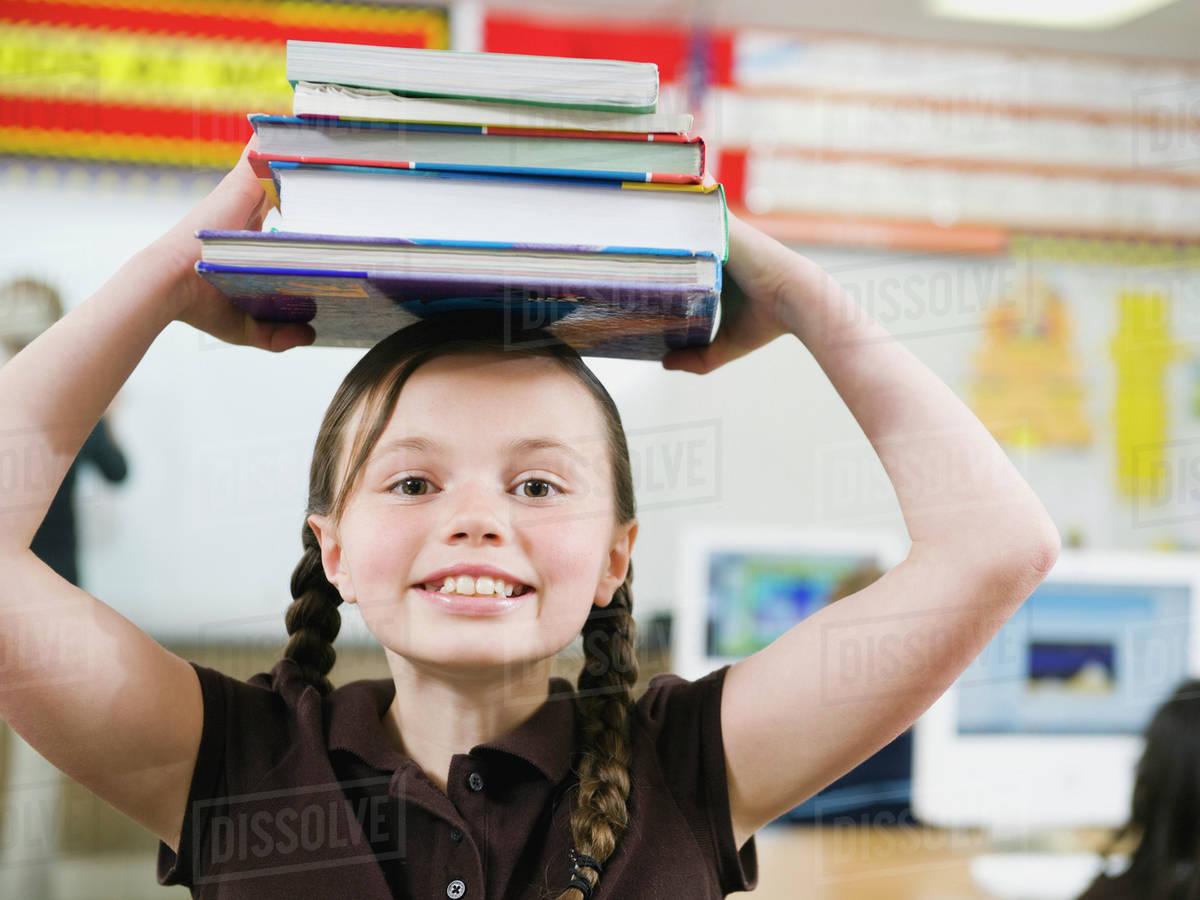 Elementary student holding a stack of books on her head - Royalty-free ...