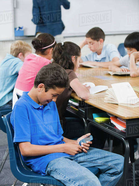 Student texting in classroom - Royalty-free Stock Photo | Dissolve