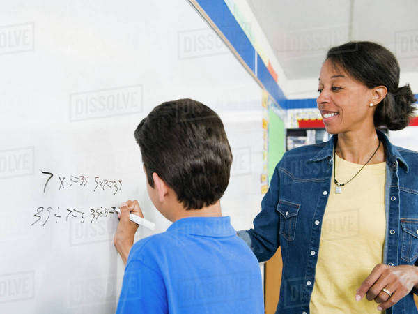 Elementary school student writing math equation on whiteboard - Stock ...