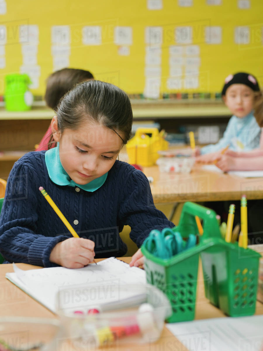 Kindergarten student writing in notebook - Stock Photo - Dissolve
