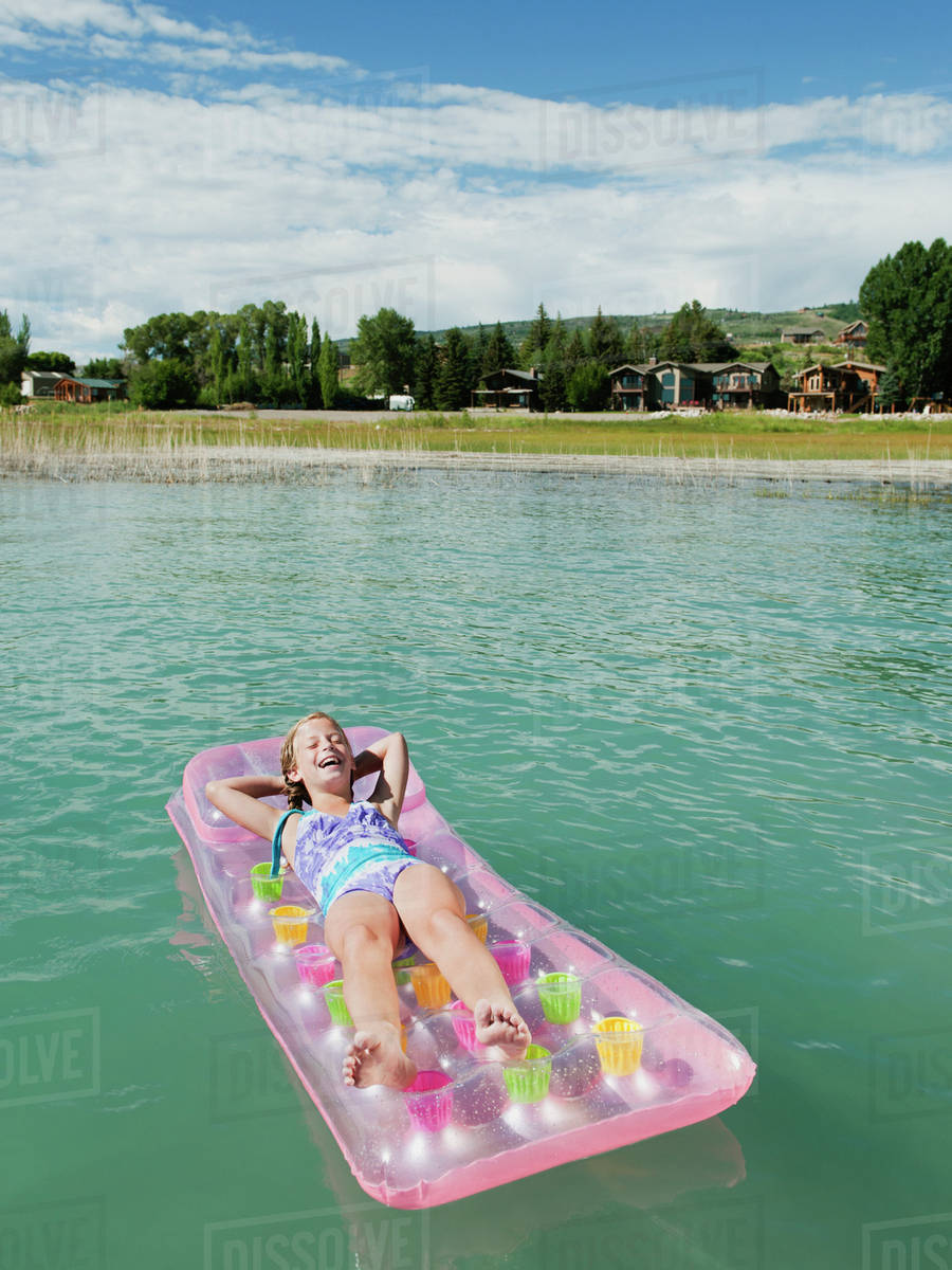Girl (8-9) floating on inflatable bed - Stock Photo - Dissolve