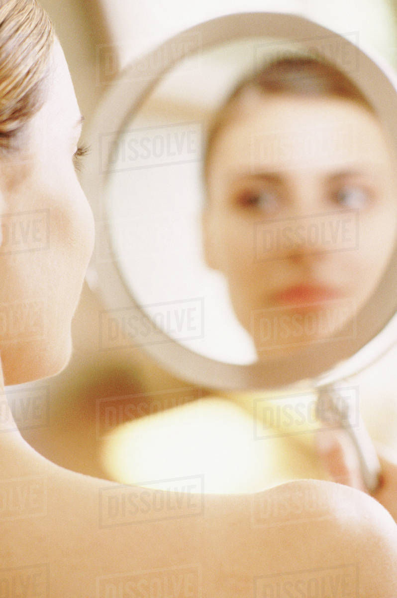 Woman looking at her reflection in a mirror - Royalty-free Stock Photo ...