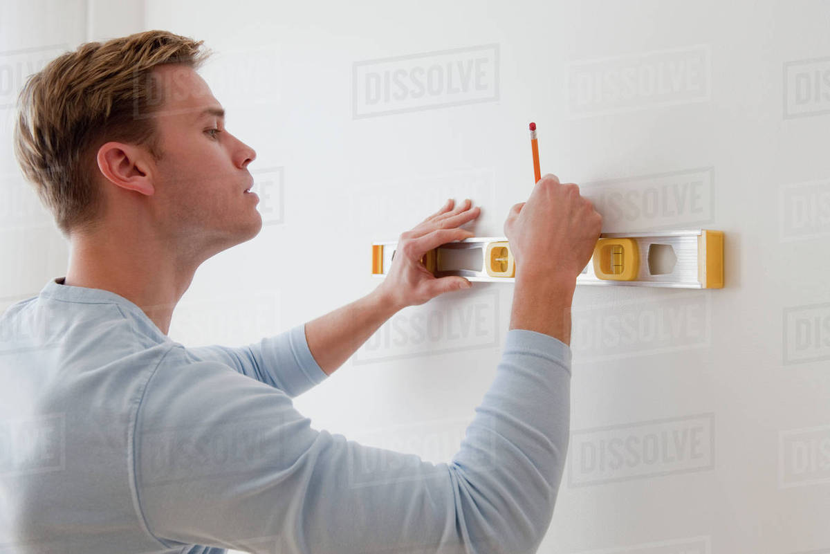 Man marking on wall with level - Stock Photo - Dissolve
