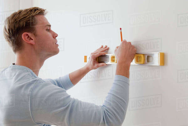 Man marking on wall with level - Stock Photo - Dissolve