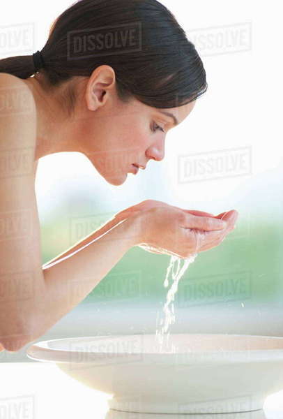 Mid-adult woman washing her face in bowl - Royalty-free Stock Photo ...