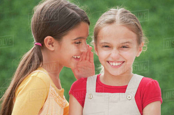 Two girl friends whispering - Stock Photo - Dissolve
