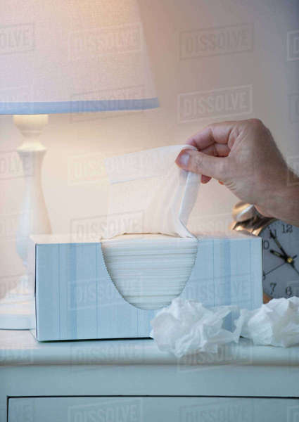 Hand pulling tissue out of box - Stock Photo - Dissolve