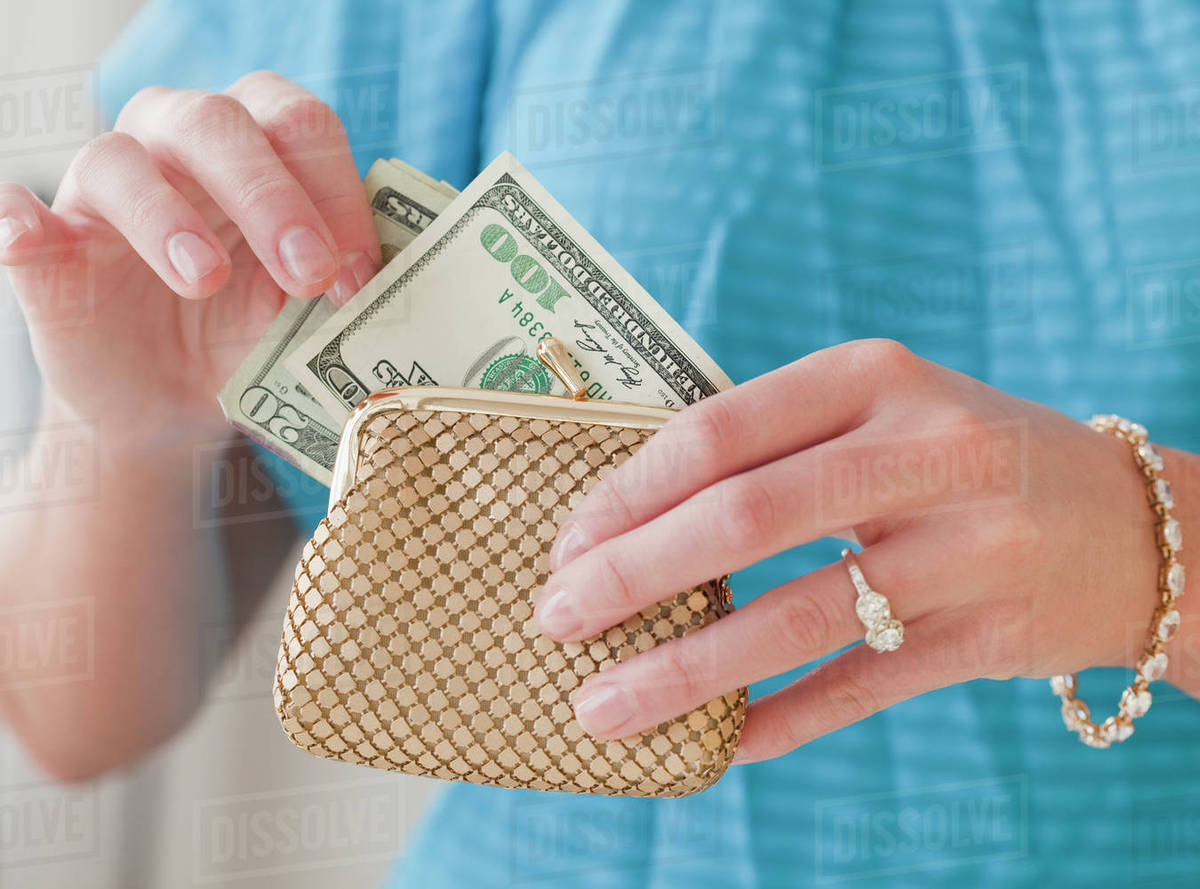 Woman pulling money from change purse - Stock Photo - Dissolve