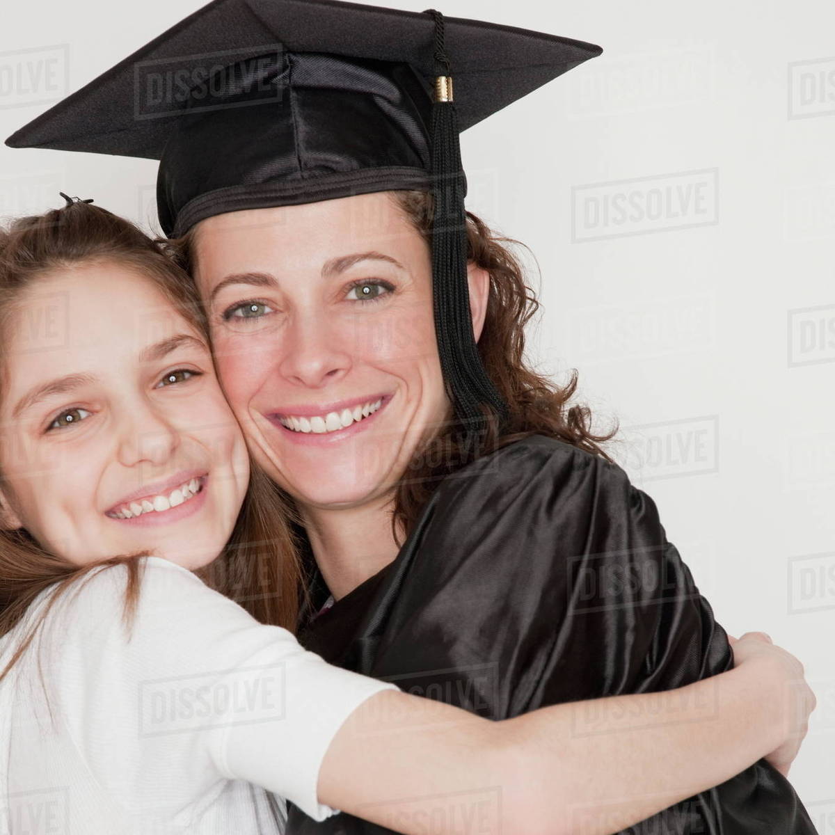 Daughter (10-12 years) embracing mother after her graduation, smiling ...